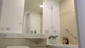 Casa de banho com chuveiro, pia e sanita. Existem sinais de segurança nas paredes.