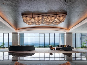Um lobby amplo com grandes janelas, piso refletivo e design de teto singular.
