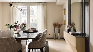 Uma sala de jantar moderna com uma mesa de vidro, cadeiras acolchoadas e um vaso com flores.