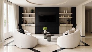 Uma sala de estar moderna com televisão de tela plana, dois poltronas brancas, uma mesa de centro e uma lareira.