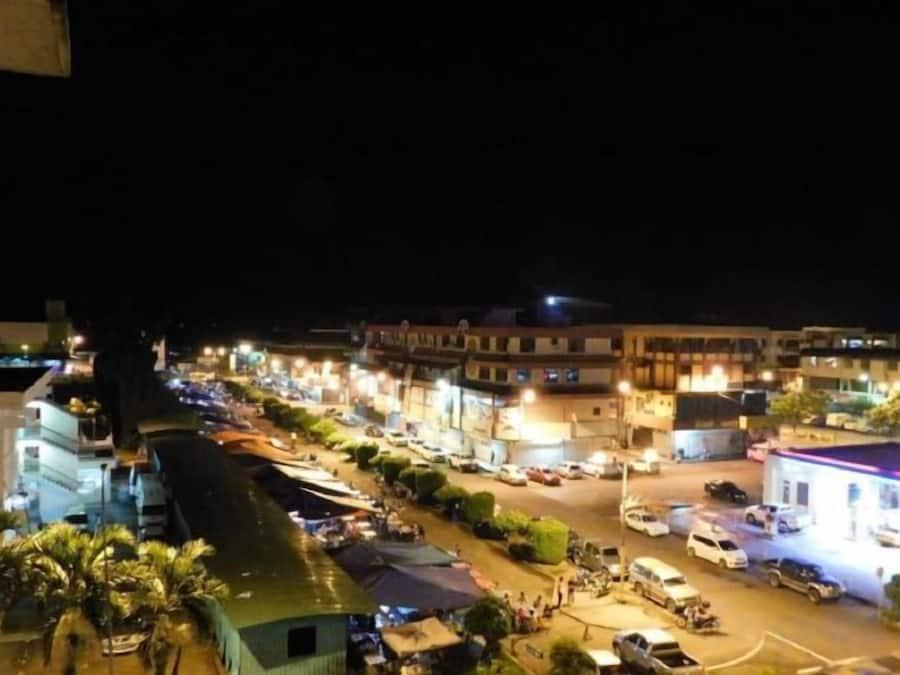 Vista noturna de uma rua com edifícios, alguns com janelas iluminadas, e alguns carros estacionados.
