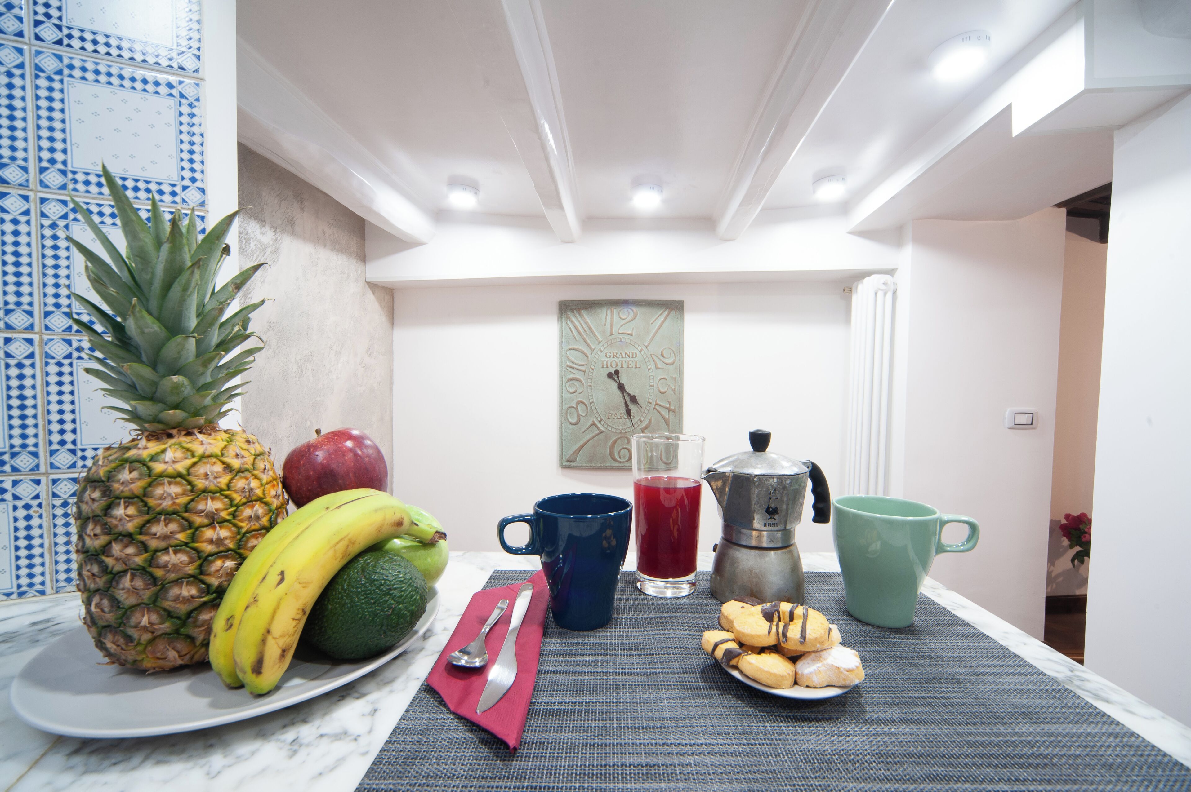 Mesa com disposição para o café da manhã: frutas, cafeteira e xícara.