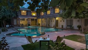 Um pátio com piscina, áreas de estar e um edifício com vários quartos.