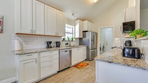 Uma cozinha moderna com armários brancos, eletrodomésticos de aço inoxidável e bancada de granito.
