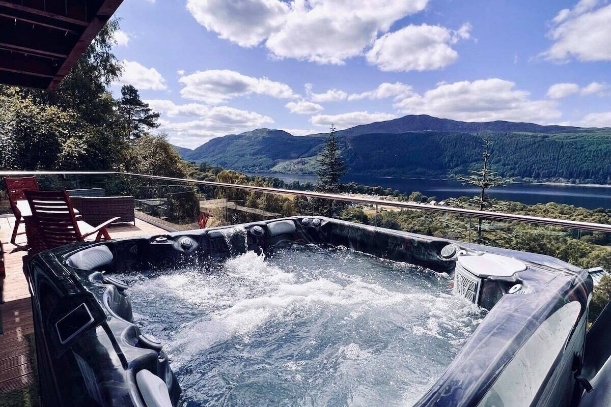 Uma banheira de hidromassagem com vista para montanhas e um lago.