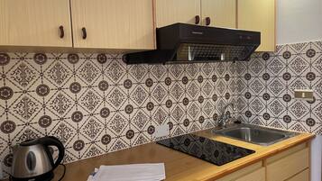 Uma cozinha com armários de madeira, chaleira de aço inoxidável, pia e azulejos decorados na parede.