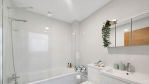 Casa de banho moderna com cabine de duche em vidro, sanita branca e toucador com espelho.