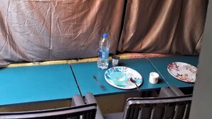 Uma mesa com toalha azul, uma garrafa de água, um prato com uma tigela, uma colher e uma xícara.