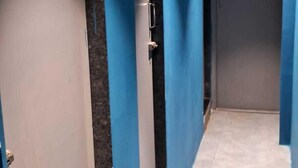 Um corredor com paredes azuis e chão de azulejos, que leva a uma porta no final.