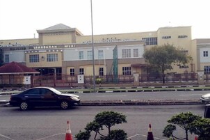 Um edifício com uma placa que diz 'BANDARAN NILAI' e um estacionamento cheio de carros.