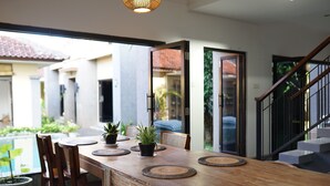 Uma sala de jantar com mesa de madeira, cadeiras e plantas em vasos.
