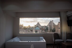 Uma casa de banho moderna com uma banheira grande, uma janela com vista para pirâmides e uma cadeira.