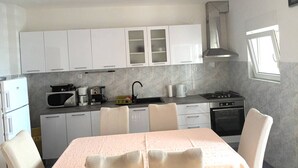 Cozinha compacta com armários brancos, fogão a gás, micro-ondas e pia.
