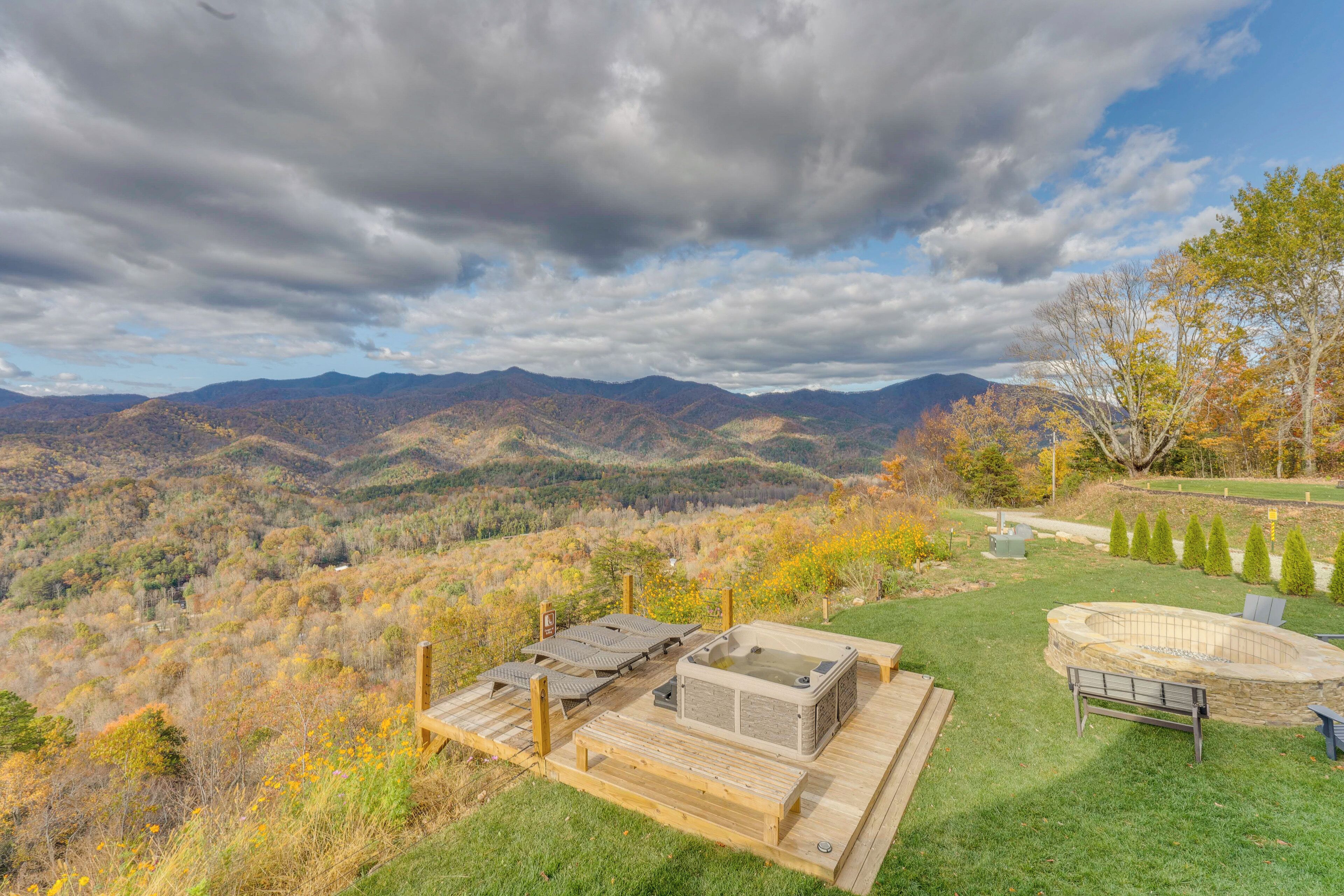 Banheira de hidromassagem e área de estar em um deck gramado, com vista panorâmica para as montanhas.