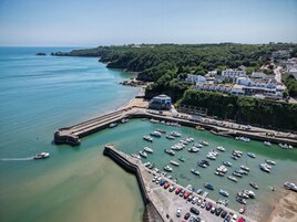 Vista aérea de uma cidade costeira com um porto de iates, um farol e edifícios residenciais.