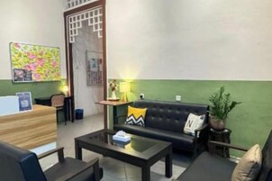 Uma área de recepção com balcão, sofá, mesa de centro e planta em vaso.