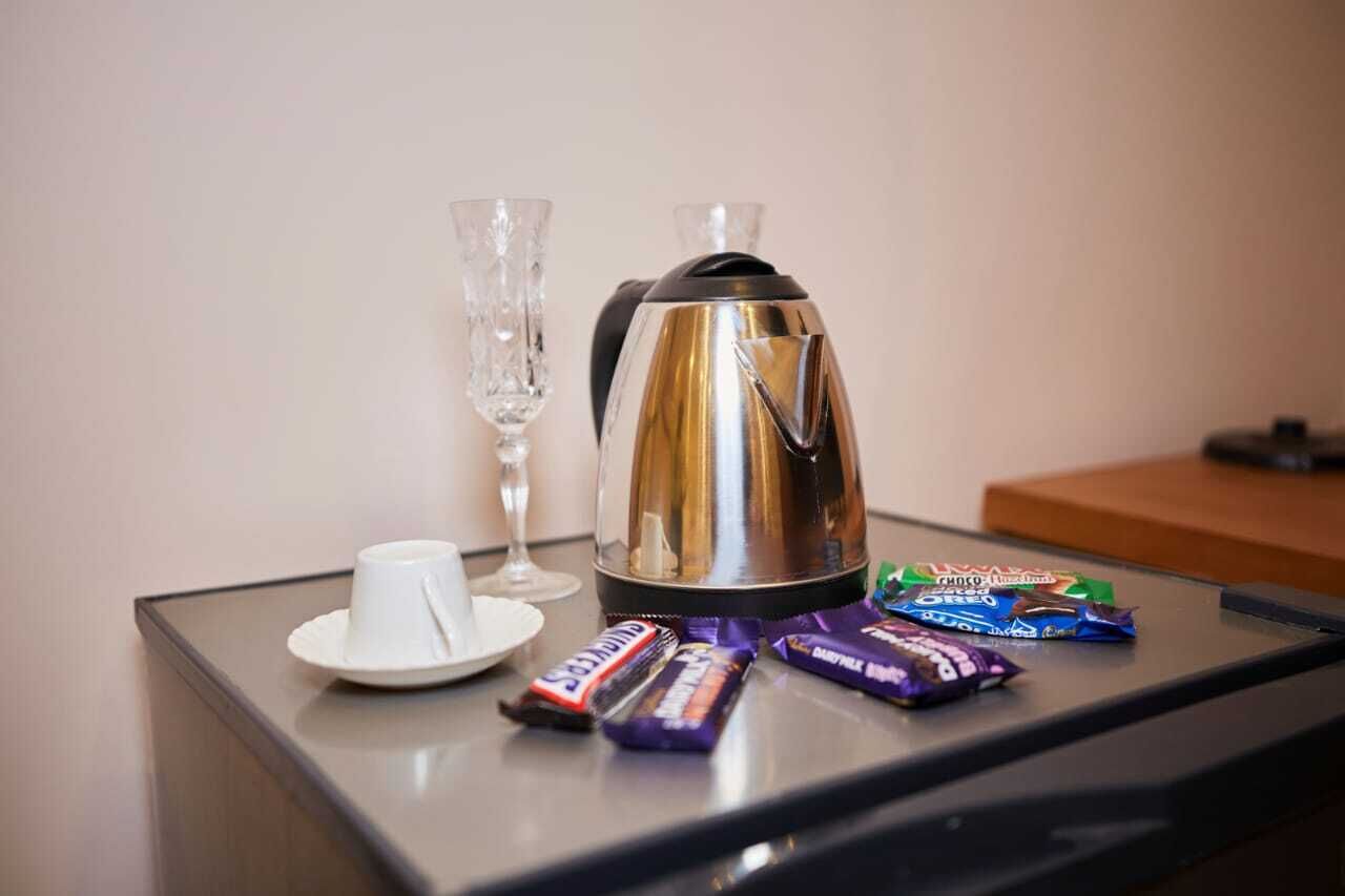 Uma mesa com uma cafeteira, um copo, uma chávena e algumas barras de chocolate.