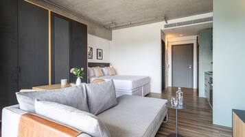 Um espaço de estar moderno com sofá, cama, pequena mesa e área de cozinha compacta.