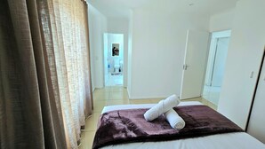 Quarto de hotel com uma cama, banheiro visível por uma porta aberta e vista para o corredor.