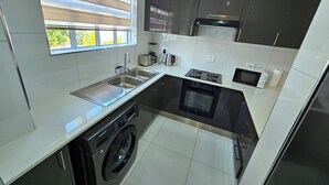 Cozinha compacta com máquina de lavar embutida, micro-ondas e fogão.