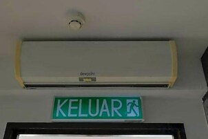 Um aparelho de ar condicionado e uma placa indicando a direção para o quarto 'KELUAR'.