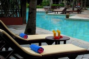 Uma área à beira da piscina com espreguiçadeiras e uma mesa com velas.