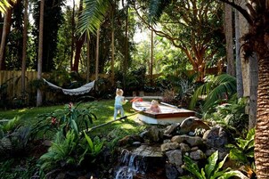 Um jardim exuberante com uma pequena cascata, uma rede e um barco.
