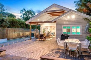 Uma casa com piscina, área de estar externa e varanda coberta.