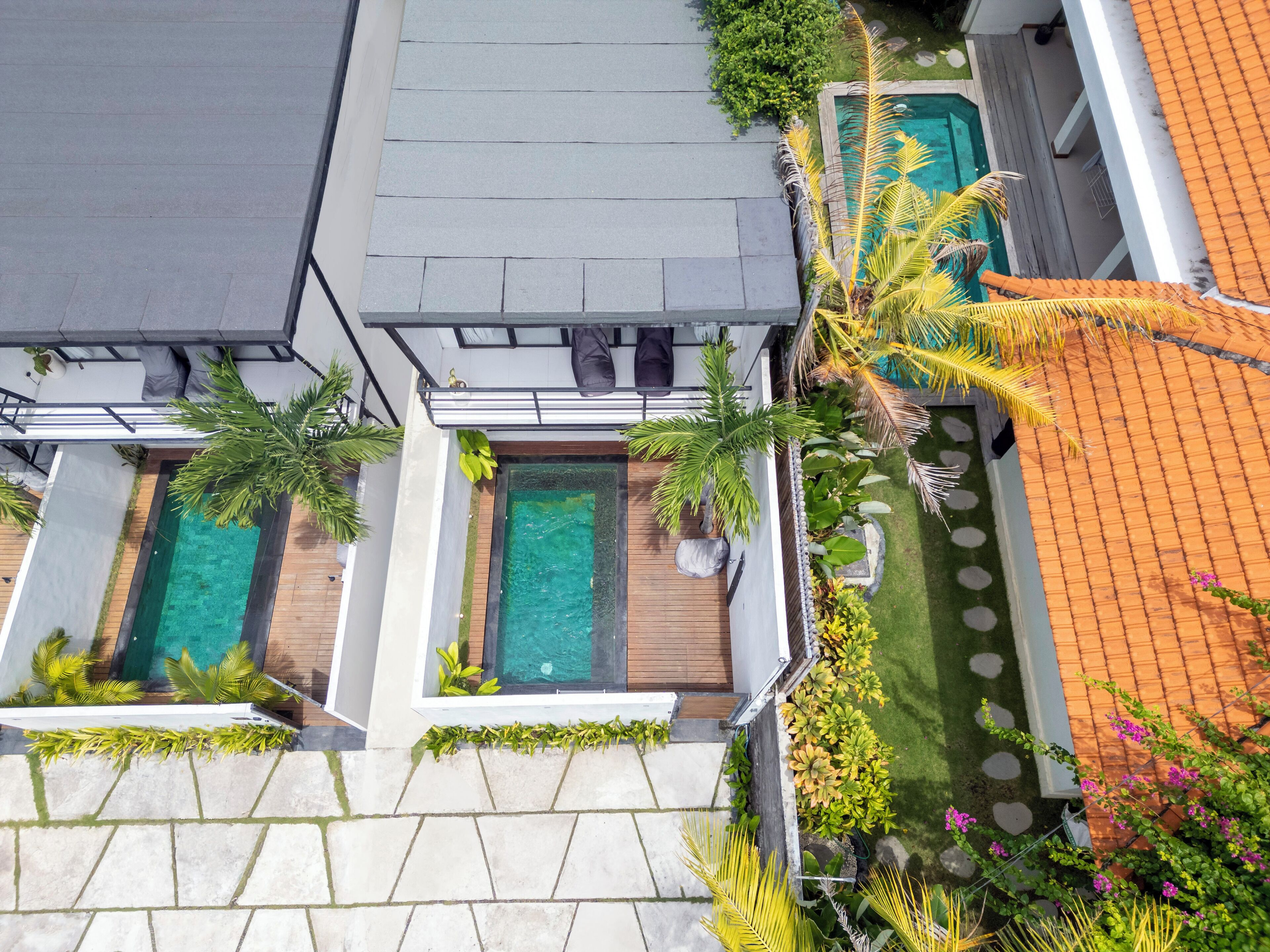 Um edifício residencial moderno com duas piscinas, um jardim no terraço e um gramado bem cuidado.