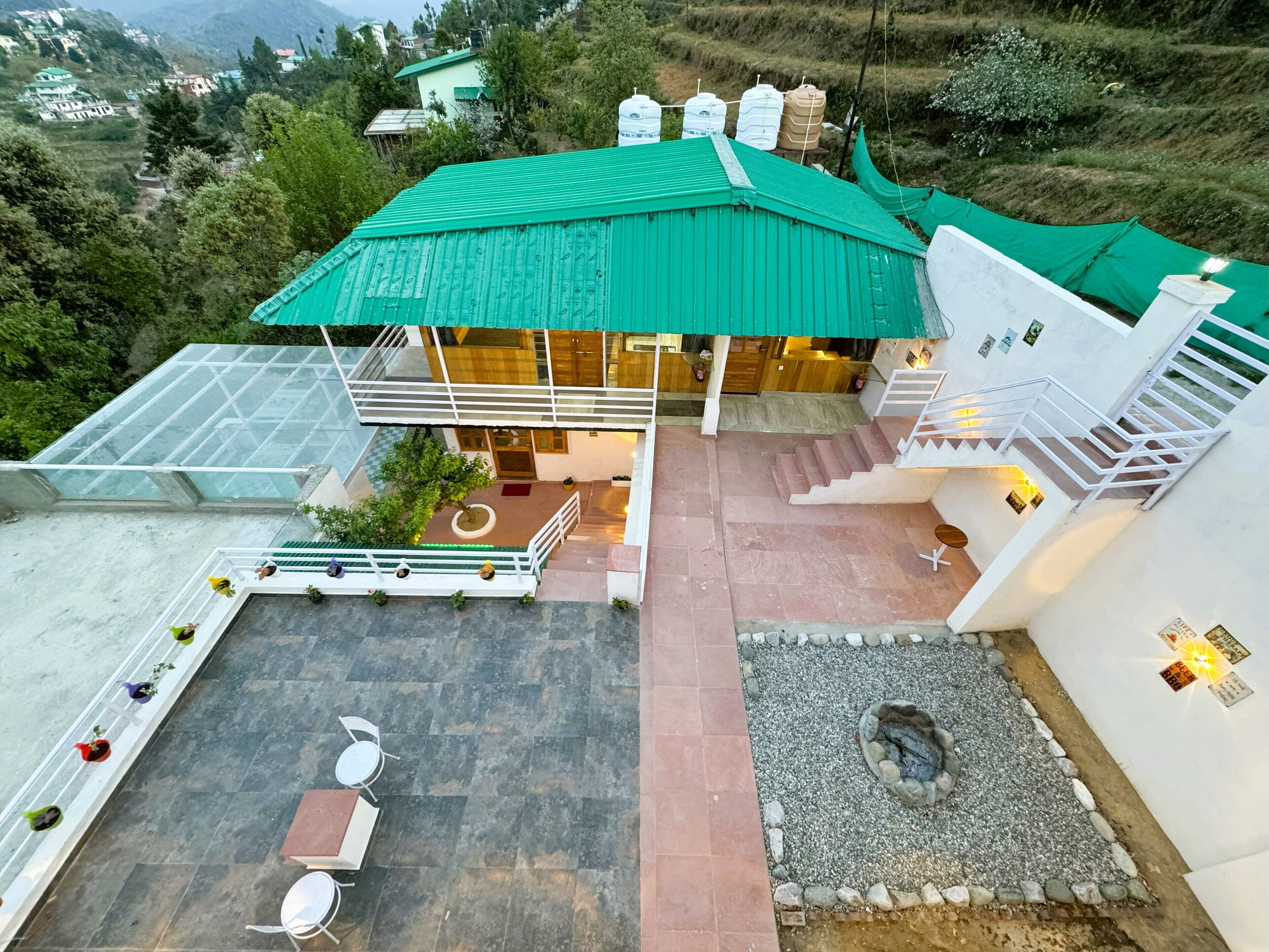 Um edifício de dois andares com telhado verde, terraço com área de estar externa e escada que leva ao andar superior.