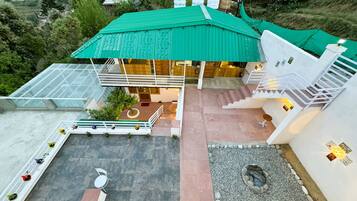 Um edifício de dois andares com telhado verde, terraço com área de estar externa e escada que leva ao andar superior.