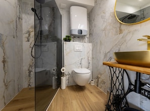 Uma casa de banho moderna com chuveiro, sanita e lavatório.