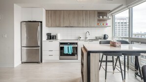 Uma cozinha moderna com frigorífico de aço inoxidável, forno e área de refeições com mesa e cadeiras.