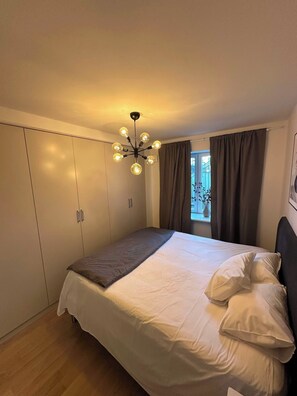 Um quarto com uma cama grande, um lustre no teto e uma janela com cortinas.