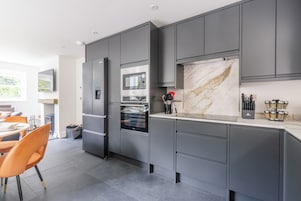 Uma cozinha moderna com armários cinza, painel de backsplash de mármore e eletrodomésticos de aço inoxidável.