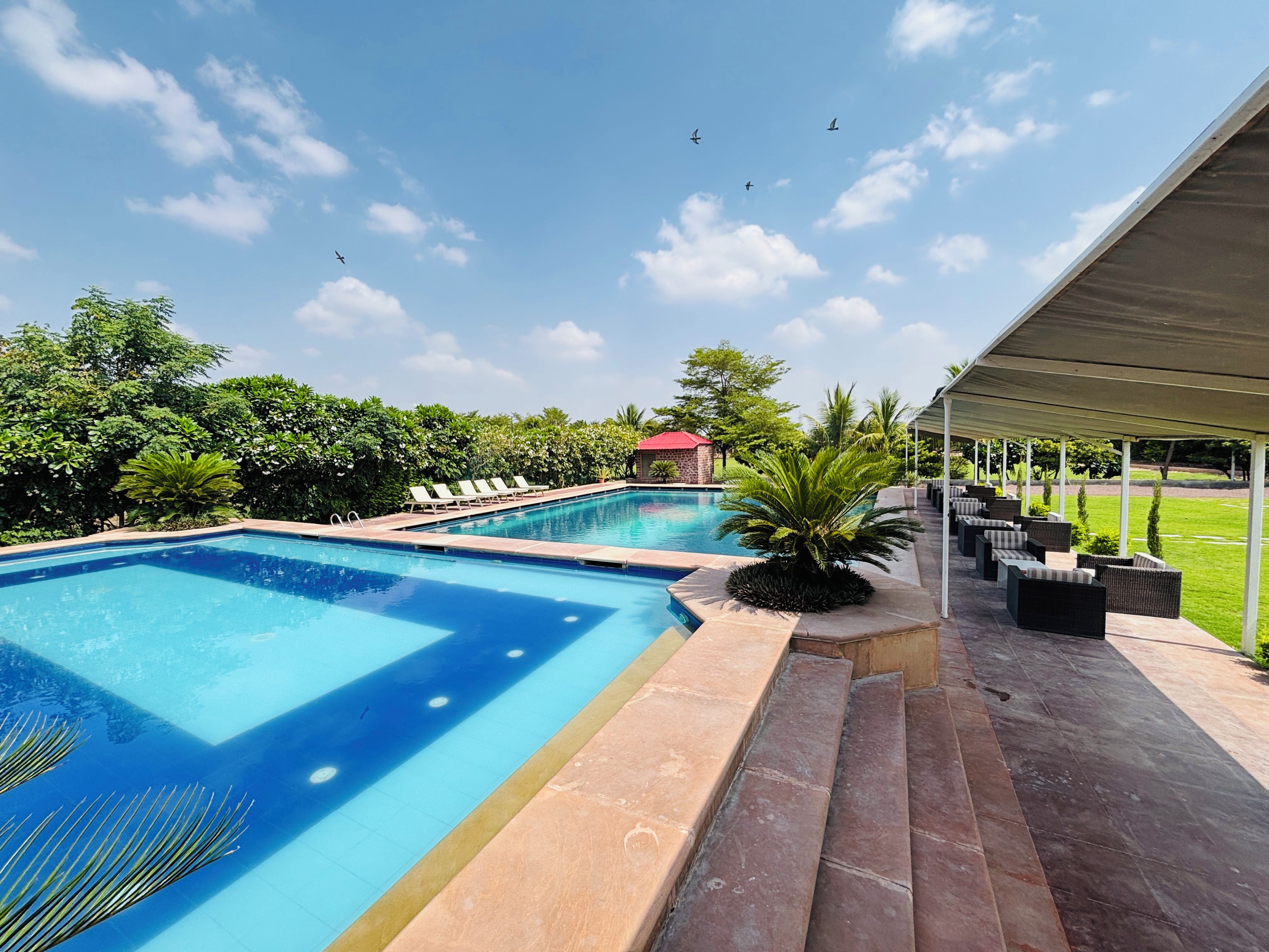 Uma piscina com espreguiçadeiras e área de estar coberta.