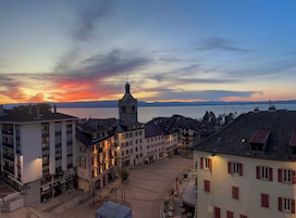 Paisagem urbana com uma torre imponente e um calçadão ao pôr do sol.