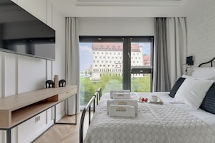 Quarto de hotel moderno com cama, escrivaninha e uma grande janela com vista para a cidade.