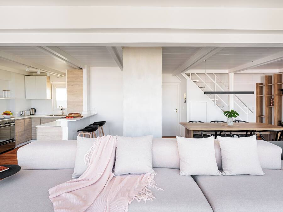 Uma sala de estar moderna com um sofá, uma mesa de centro e uma escada que leva a um andar superior.