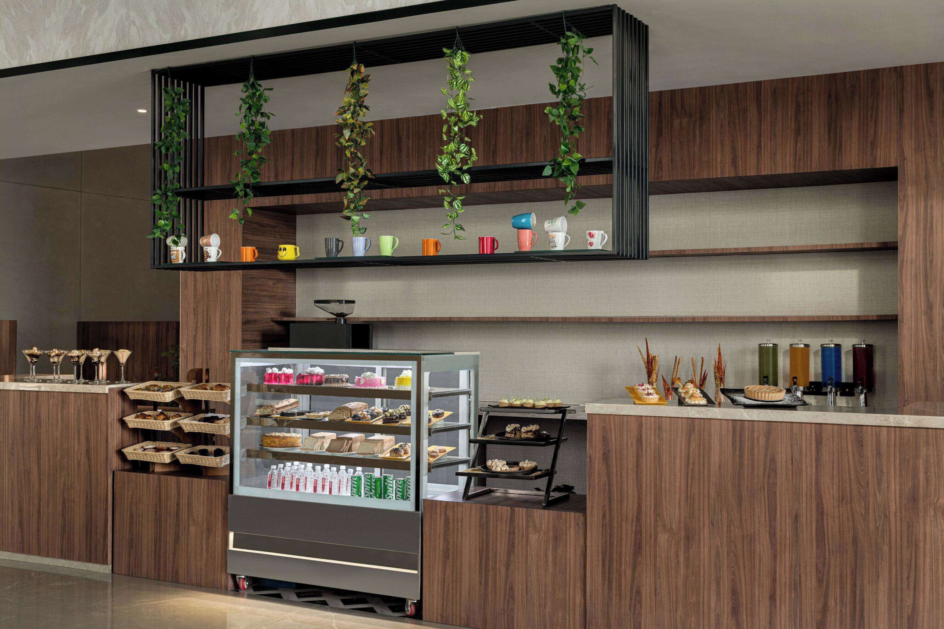 Cozinha moderna com geladeira embutida, prateleiras com diversos objetos e plantas penduradas.