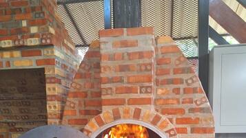Forno de pizza de tijolos com fogo aceso no interior.