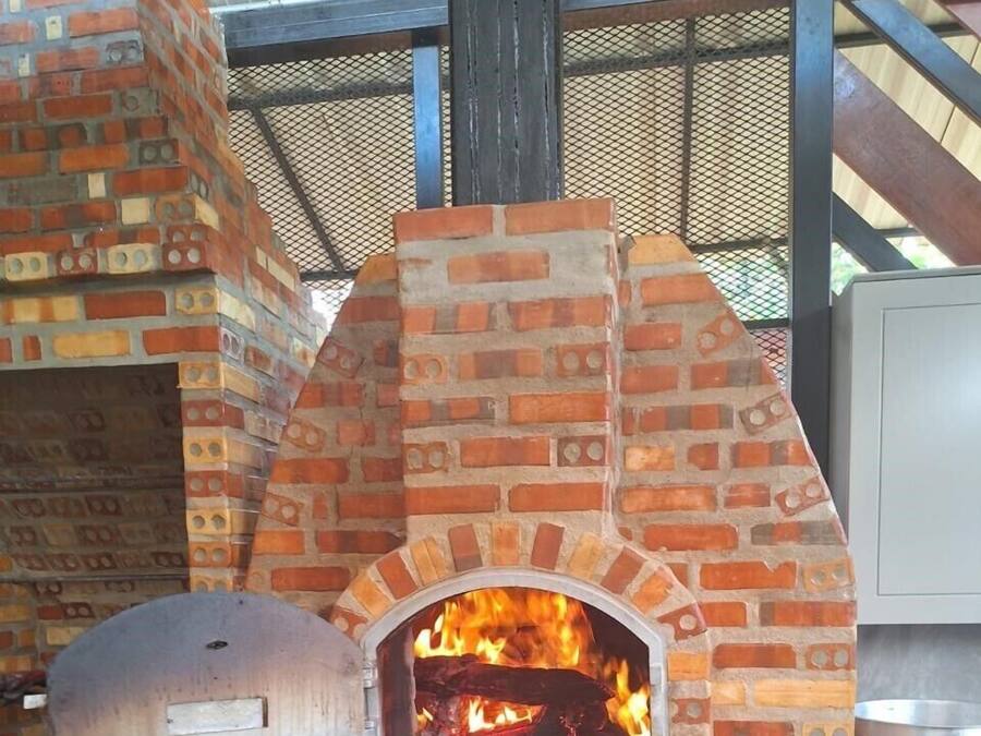 Forno de pizza de tijolos com fogo aceso no interior.