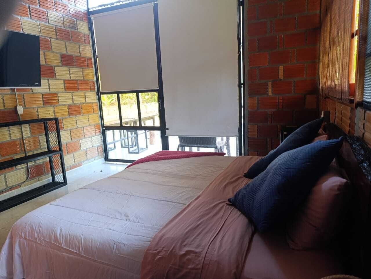 Quarto com cama, televisão na parede e varanda com vista.