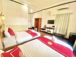 Quarto de hotel com duas camas, uma escrivaninha, uma cadeira, uma televisão e um aparelho de ar condicionado.