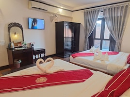 Quarto de hotel com duas camas, televisão, guarda-roupa e janela com cortinas.
