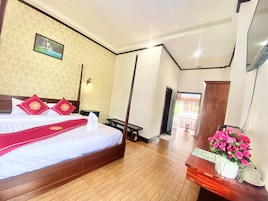 Quarto de hotel com cama, mesa de cabeceira, piso de madeira, quadro na parede e vista para o exterior.