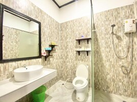 Casa de banho com lavatório branco, sanita, chuveiro e espelho.