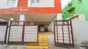 Uma entrada com portão e escadaria que leva a um edifício com a placa "Sri Saro".