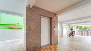 Um espaço amplo e coberto com chão de azulejos, um elevador fechado e uma motocicleta estacionada do lado de fora.