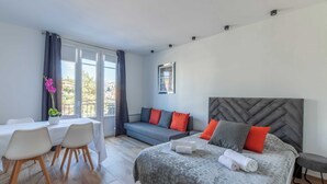 Quarto de hotel moderno com cama, sofá, mesa de jantar e cadeiras.